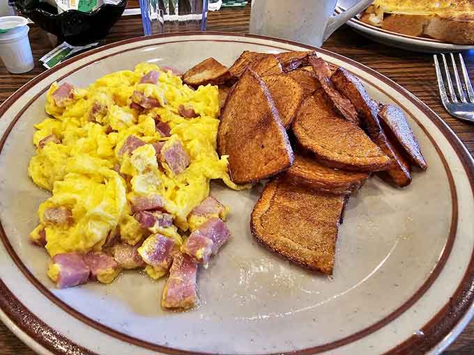 A hearty breakfast plate with scrambled eggs, ham, and toast proves that simple, well-executed comfort food never goes out of style.