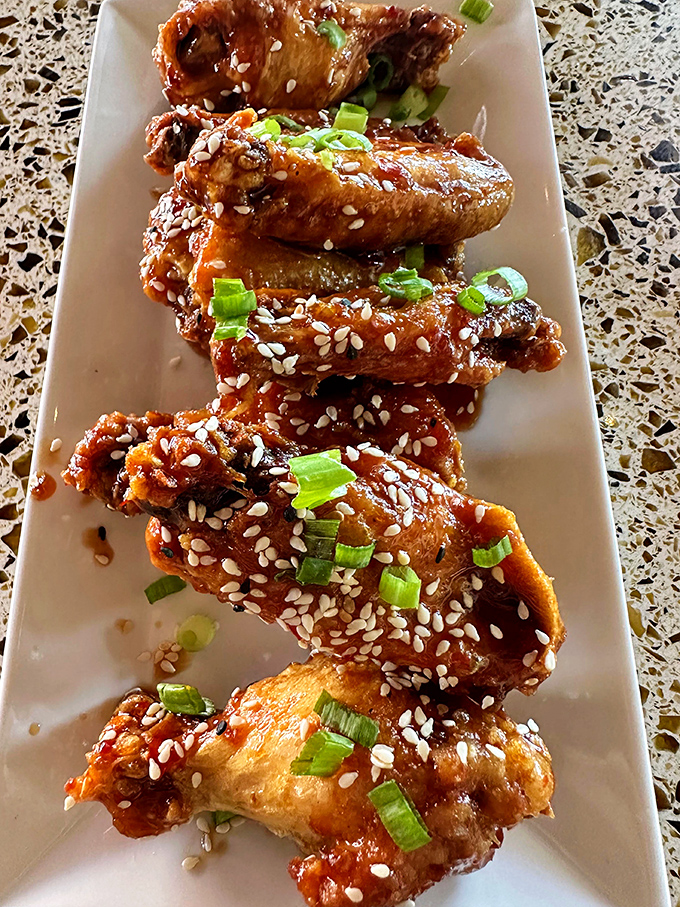 These glazed chicken wings, sprinkled with sesame seeds and green onions, offer the perfect balance of sticky-sweet exterior and juicy interior.