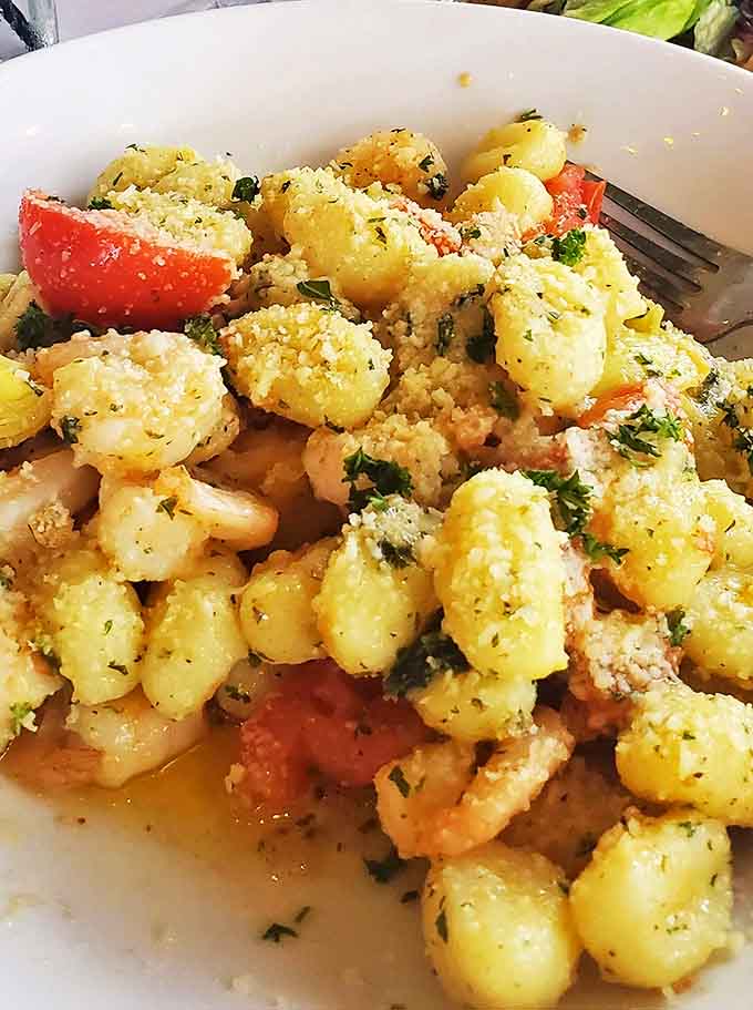 Pillowy gnocchi nestled among tomatoes and herbs, dusted with Parmesan &ndash; comfort food elevated to art form status on a simple white plate.