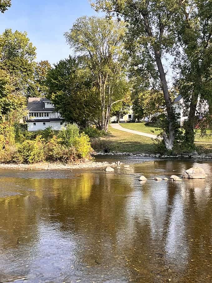 Nature and history converge where the river creates a mirror for the trees, stones forming natural stepping paths across the shallow waters.