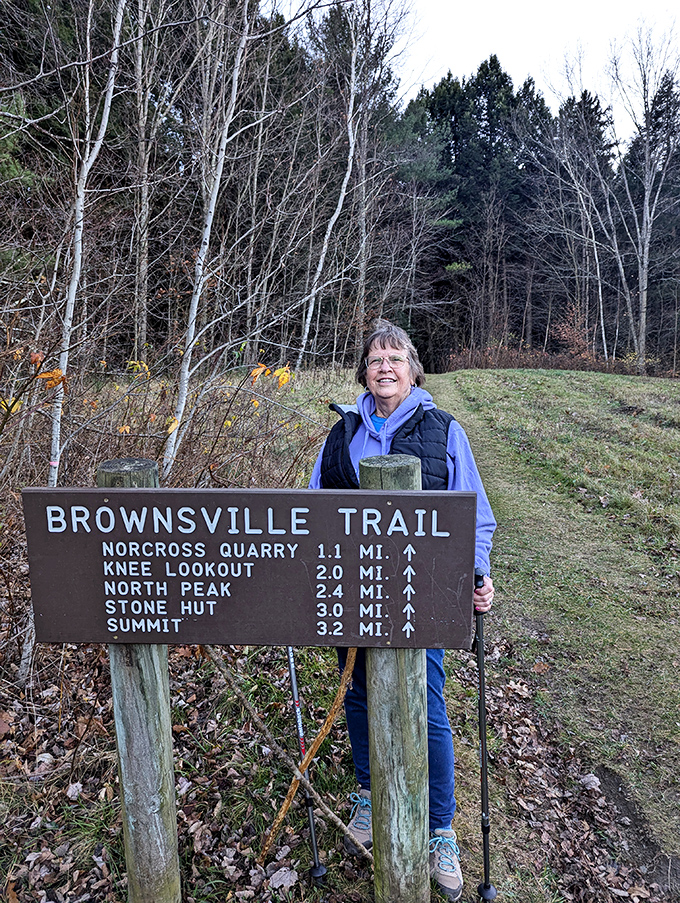 A happy hiker marking the trailhead, that smile saying "3.2 miles to the summit? Challenge accepted!"