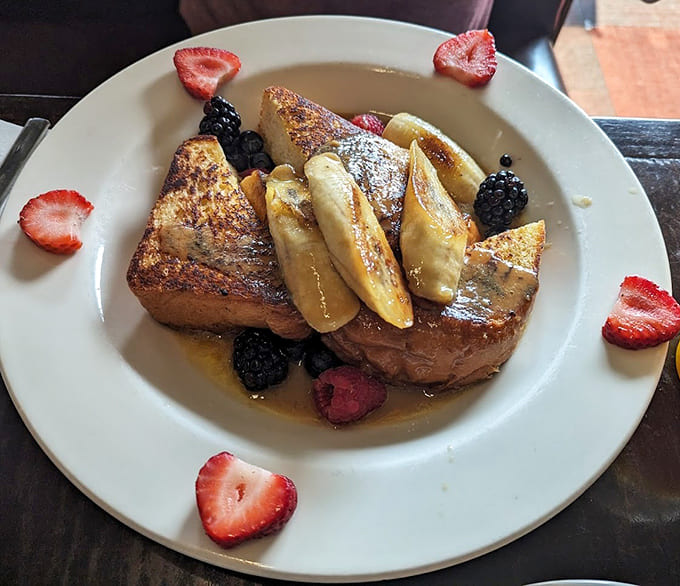 Brioche French toast topped with caramelized bananas and berries, proving that bread can absolutely be the star of the show.