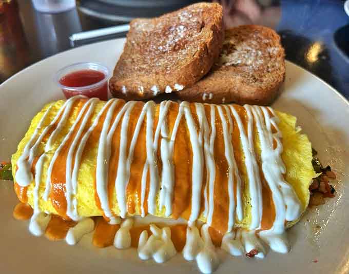 The Mexican Omelet arrives with artistic sauce drizzles that suggest someone in the kitchen moonlights as a breakfast Picasso with better taste.