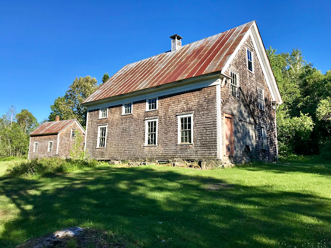 This historic building stands proudly against blue skies, wearing its weathered wood siding like a badge of honor.