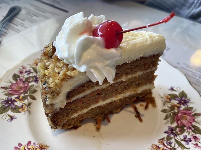 That carrot cake stands tall and proud, layers of spiced perfection topped with a cherry that's basically the exclamation point on your meal.