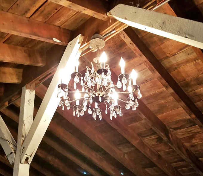 Crystal chandeliers hang from rustic wooden beams, creating that perfect marriage of elegance and country charm that designers charge thousands to replicate.