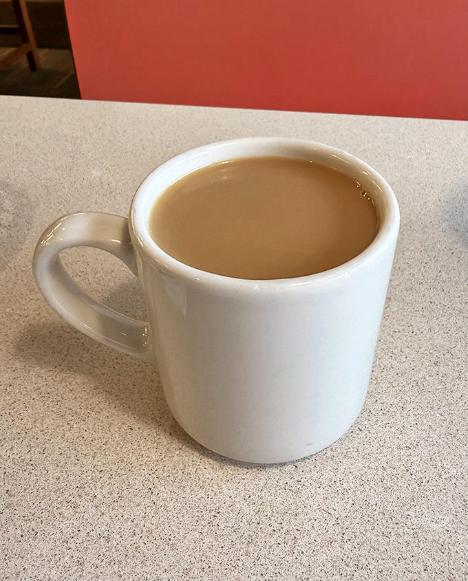 The humble white mug contains nothing fancy, just honest coffee that keeps flowing as long as conversations do.