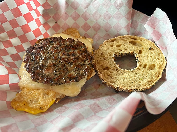 The Cowboy Dan sandwich opens wide to reveal its secrets: a juicy patty and melted cheese nestled between golden bagel halves.