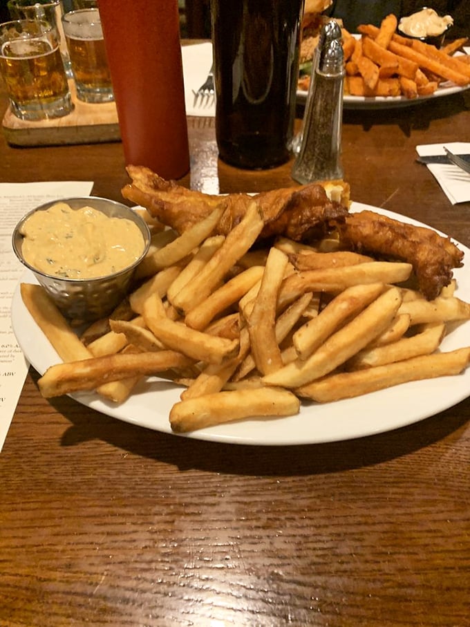 Golden-battered fish rests on a mountain of crispy fries, with house-made tartar sauce standing by for its supporting role.