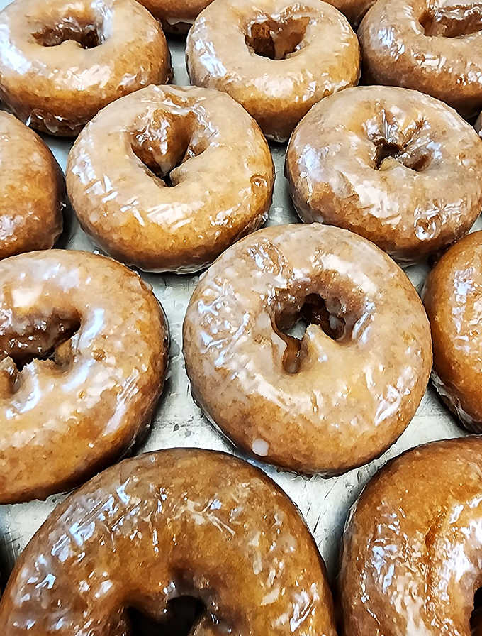 The glazed donuts glisten in the morning light, their perfect sheen promising the ideal balance of sweetness and that distinctive yeasty chew.