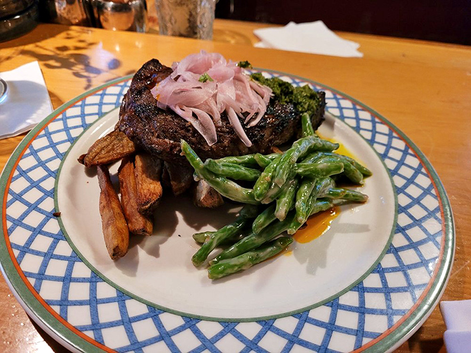 A perfectly grilled ribeye shares the plate with crisp fries and vibrant green beans&mdash;proof that classics can still surprise.