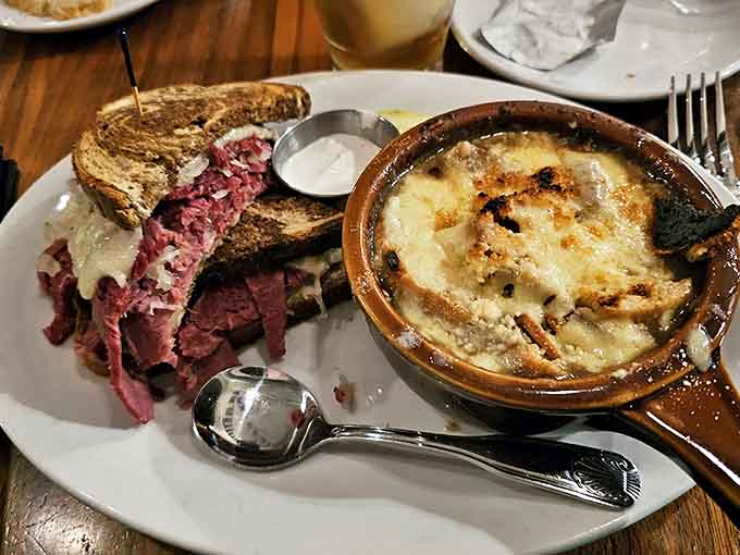 A match made in culinary heaven: rich Guinness-infused French onion soup alongside a perfectly stacked corned beef sandwich &ndash; comfort food that hugs your soul.