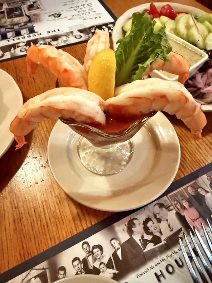 The shrimp cocktail presents plump pieces perched elegantly on a glass rim, ready for their dip in zesty cocktail sauce.