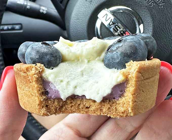 The dramatic cross-section reveals the blueberry tart's hidden secrets &ndash; a purple-tinged filling beneath creamy topping and fresh berries.