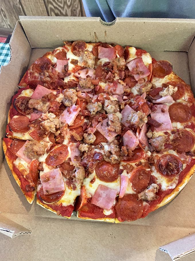 A carnivore's dream where pepperoni, sausage, and ham throw a party on perfectly melted cheese and that legendary homemade crust.