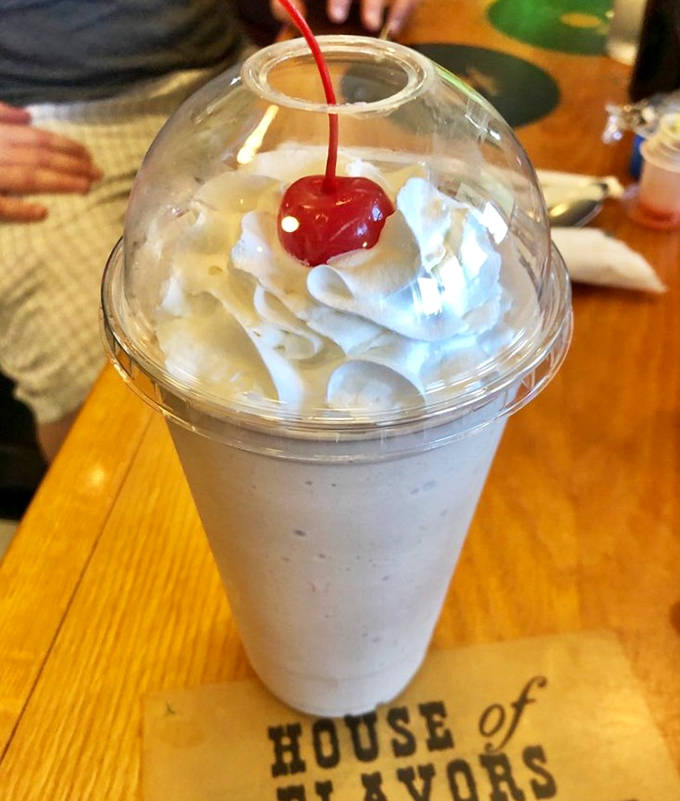 Whipped cream peaks crowned with a cherry sentinel – this milkshake isn't just a drink, it's a dessert skyscraper.