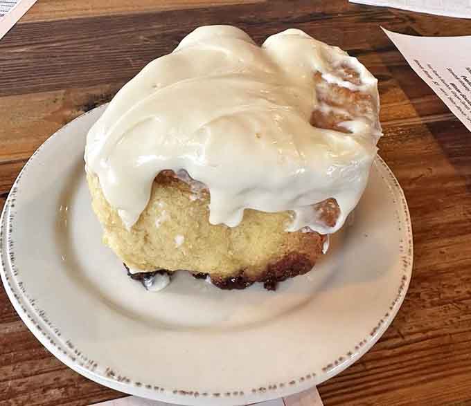 This cinnamon roll is roughly the size of a small planet and covered in enough frosting to make your dentist schedule an intervention.