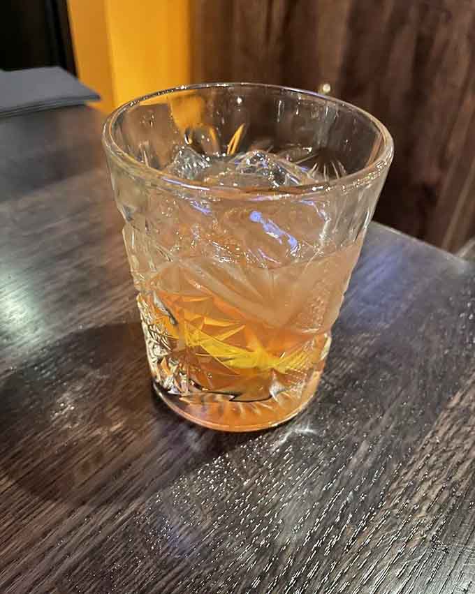 An Old Fashioned sits waiting, amber liquid catching the light like liquid gold in a glass, smooth and sophisticated.