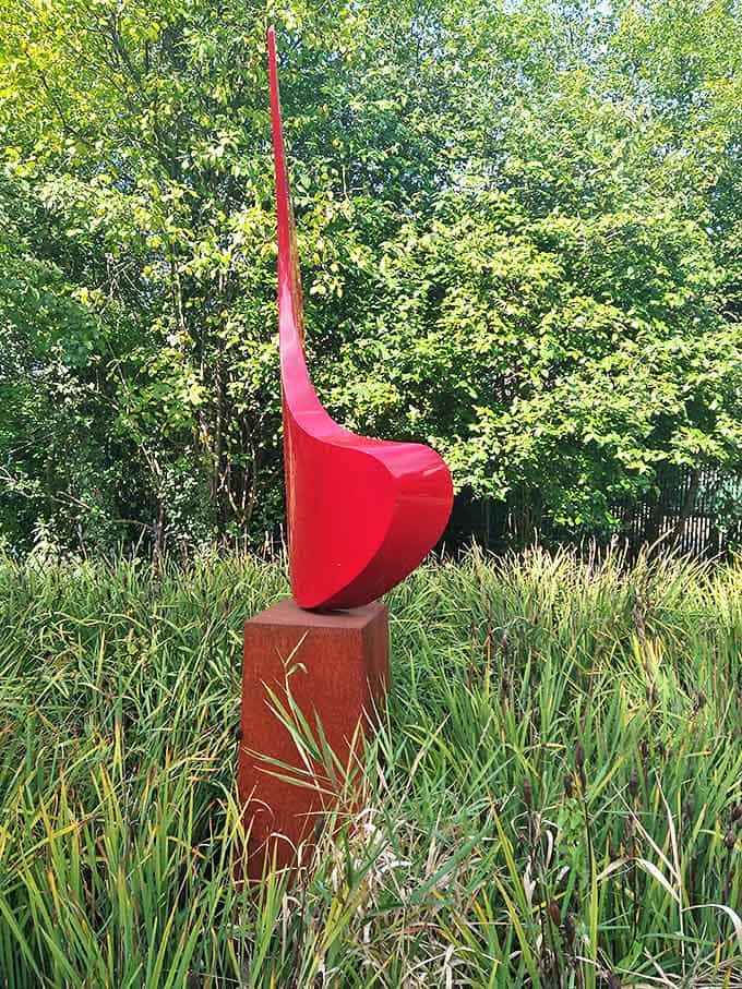 The bold red fin cuts through space with dramatic flair, its sweeping curve creating a visual exclamation point against green grasses.