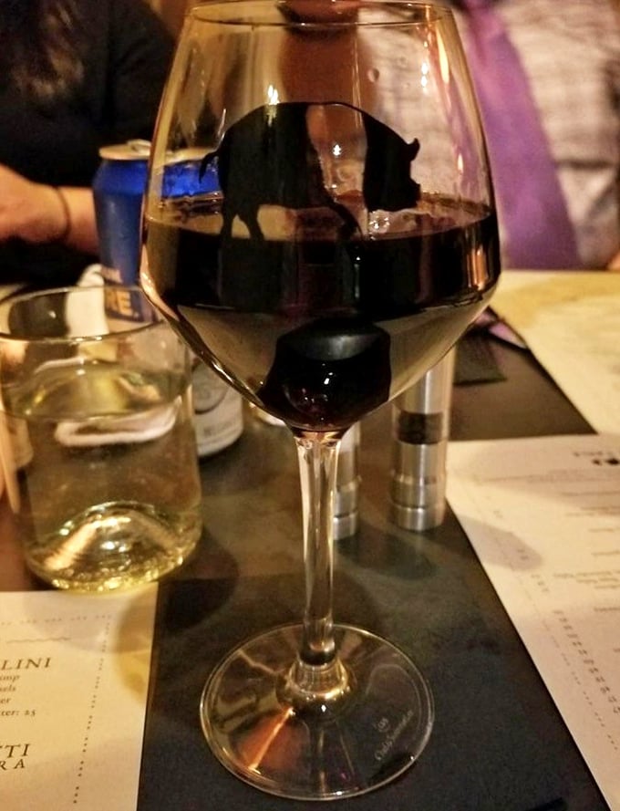 A glass of robust red wine, complete with the restaurant's playful pig logo &ndash; because what's an Italian feast without the perfect vino companion?
