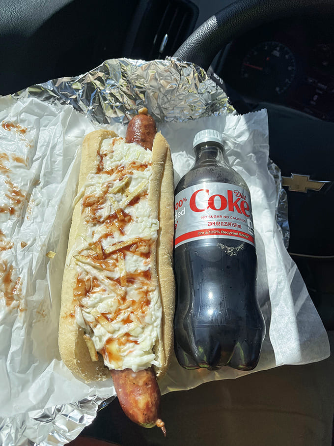 The perfect car picnic &ndash; a juicy sausage nestled in a fresh roll with toppings, paired with an ice-cold Coke.