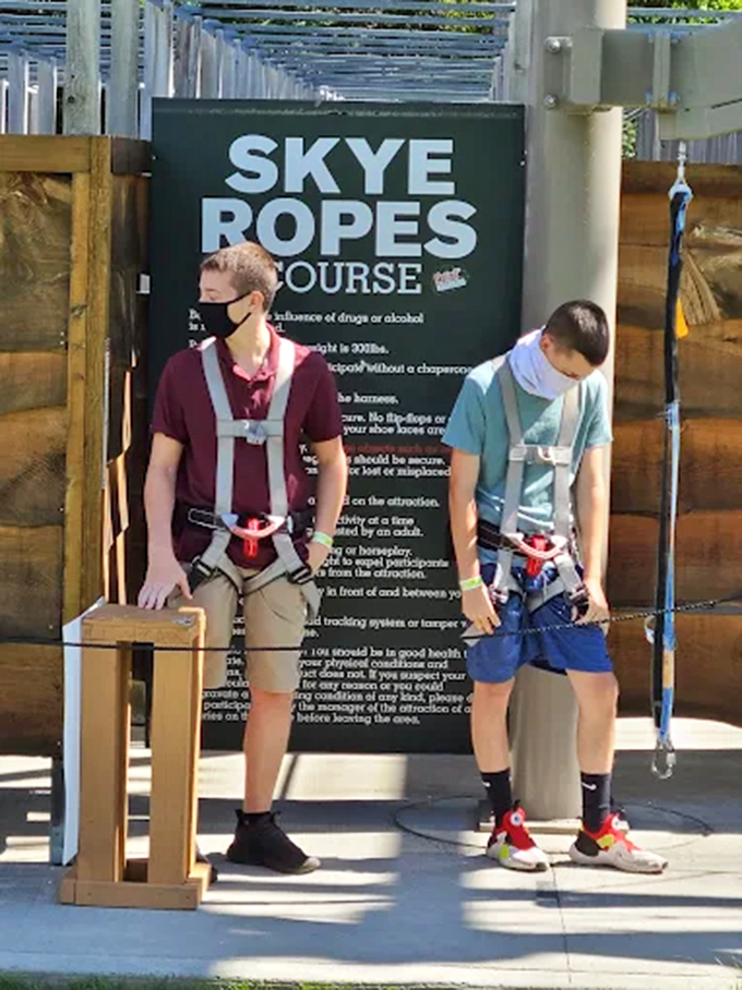 The entrance sign outlines safety guidelines while two adventurers prepare to embark on their aerial journey.