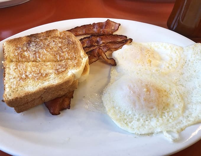 Simple perfection on a plate with fluffy eggs, crispy bacon, and golden toast proving that breakfast doesn't need complications to satisfy completely.