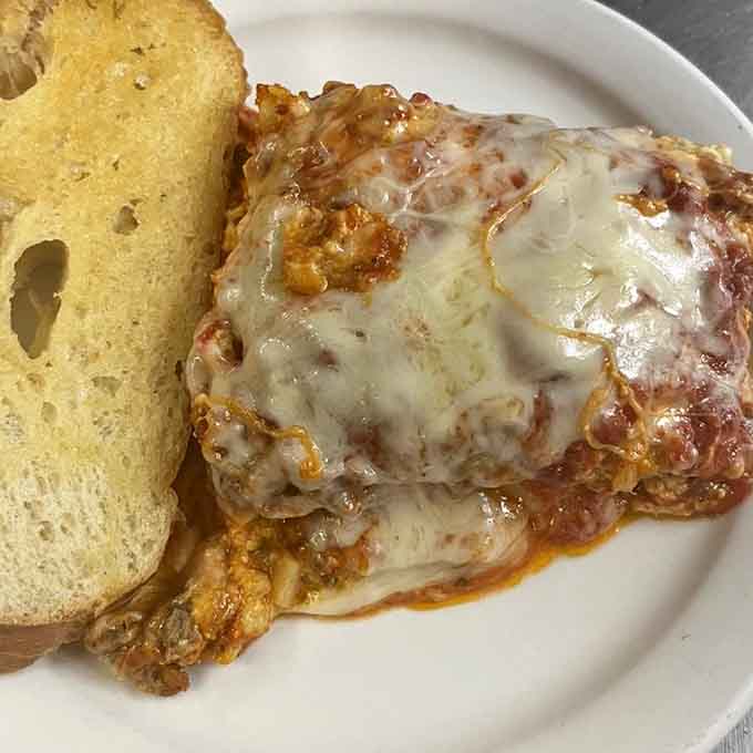 Bubbling lasagna topped with melted cheese and served with garlic bread delivers Italian-American comfort food at its finest.