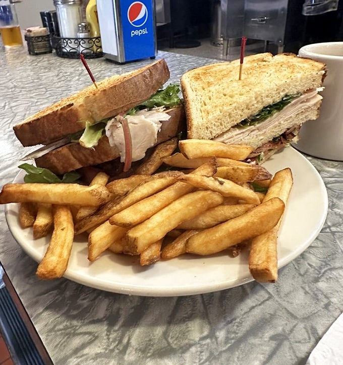 This turkey club sandwich doesn't mess around &ndash; triple-decker construction with fresh turkey, crisp bacon, and all the fixings, escorted by a golden army of perfect fries.