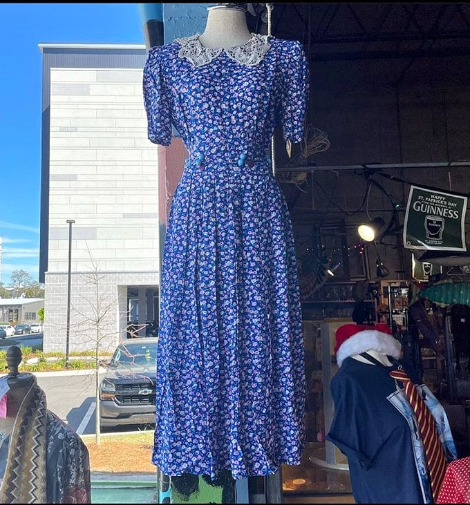 A blue floral vintage dress waits patiently for its next adventure, perhaps a garden party or wedding where it will once again be the belle of the ball.