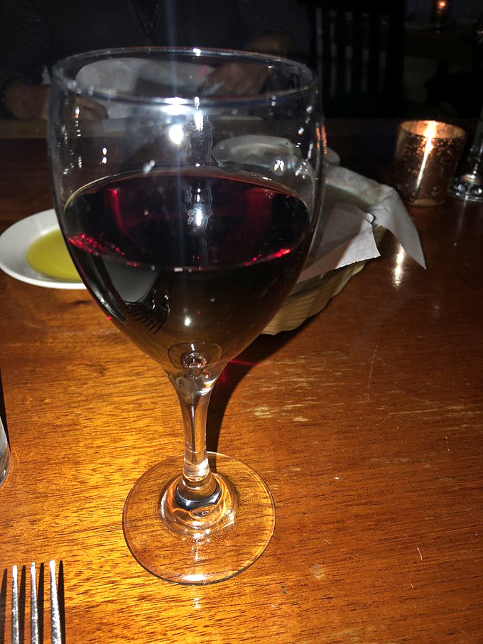 A glass of ruby-red wine catches the light, promising to be the perfect companion to your Italian feast.