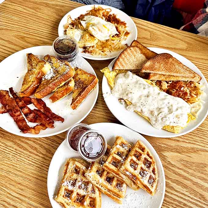 Morning glory on multiple plates! French toast, eggs smothered in gravy, and waffles – a breakfast spread worthy of a celebration.