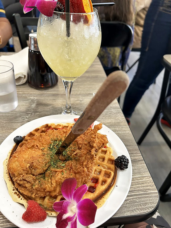 Crispy fried chicken meets golden waffle in a sweet-savory romance, garnished with berries and that signature purple orchid &ndash; brunch doesn't get better than this.
