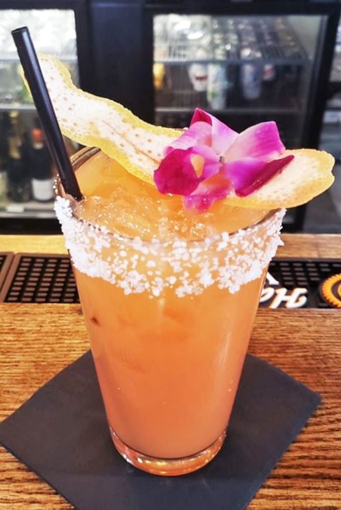 This vibrant cocktail, garnished with a fresh flower and salt rim, transforms happy hour into a truly happy experience for both eyes and taste buds.
