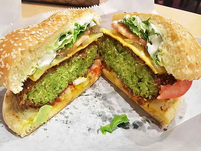 Cut into this falafel burger and witness the vibrant green interior &ndash; proof that vegetables can be the star of the show.