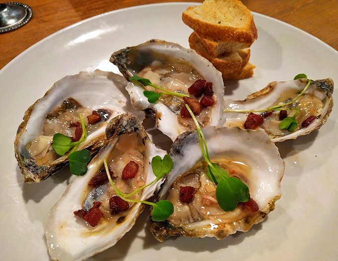 Fresh oysters adorned with bacon bits and microgreens &ndash; the ocean's perfect gift, enhanced just enough to make you appreciate its natural beauty.