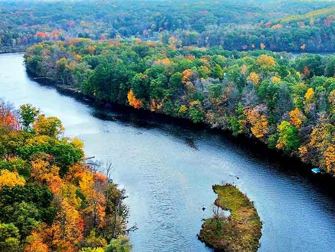 The mighty river curves through autumn's palette, carrying both water and whispers of Michigan's rich natural history.