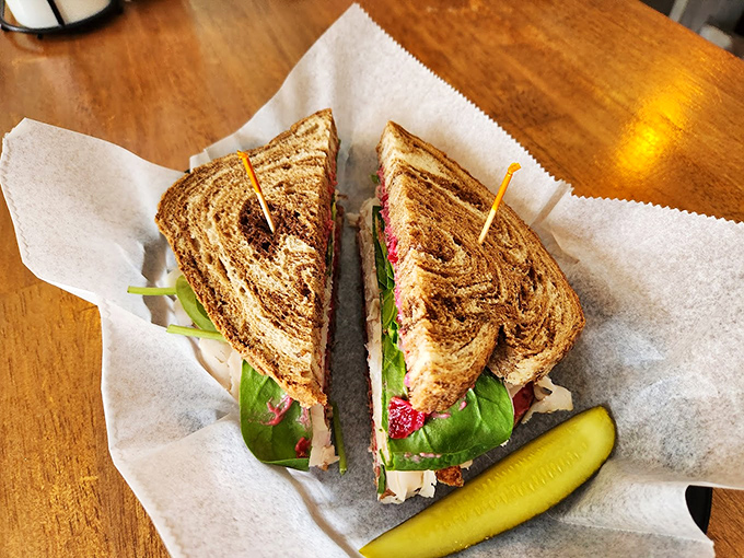 A sandwich served with pickle protocol: perfectly cut, expertly stacked, and presented on parchment paper. Lunch diplomacy at its finest.
