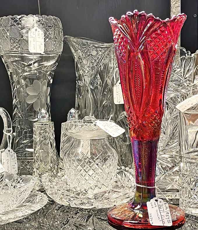 That red vase is giving serious Victorian drama while the crystal pieces around it sparkle like they're auditioning for a period film.
