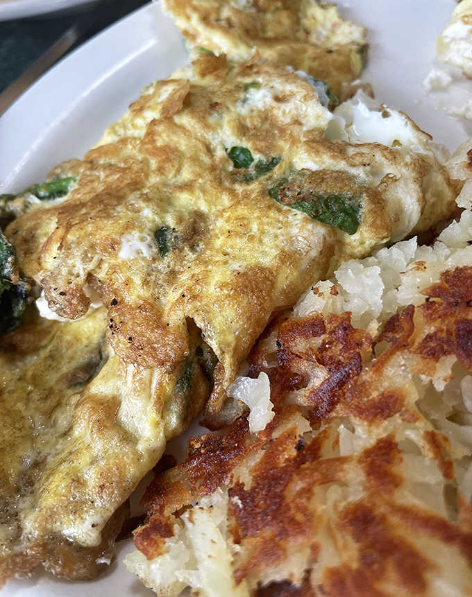 A perfectly executed Denver omelette with ham, peppers, onions, and cheese, served alongside golden hash browns for breakfast perfection.