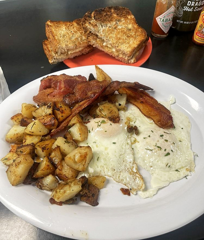 The classic two eggs and meat breakfast with homefries and toast, looking exactly how this plate should look, with proper portions and nothing apologizing for being breakfast food.