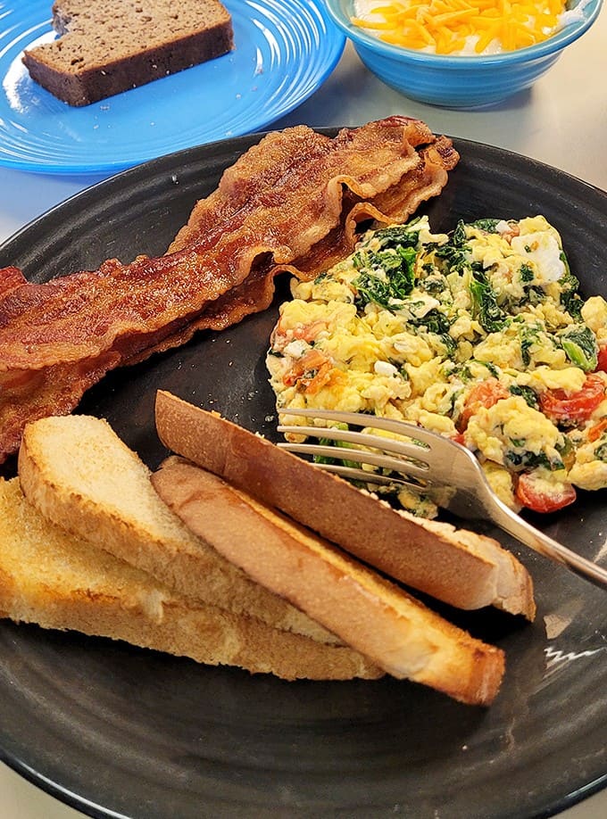 Crispy bacon, fluffy scrambled eggs with veggies, and golden toast create the holy trinity of breakfast perfection.