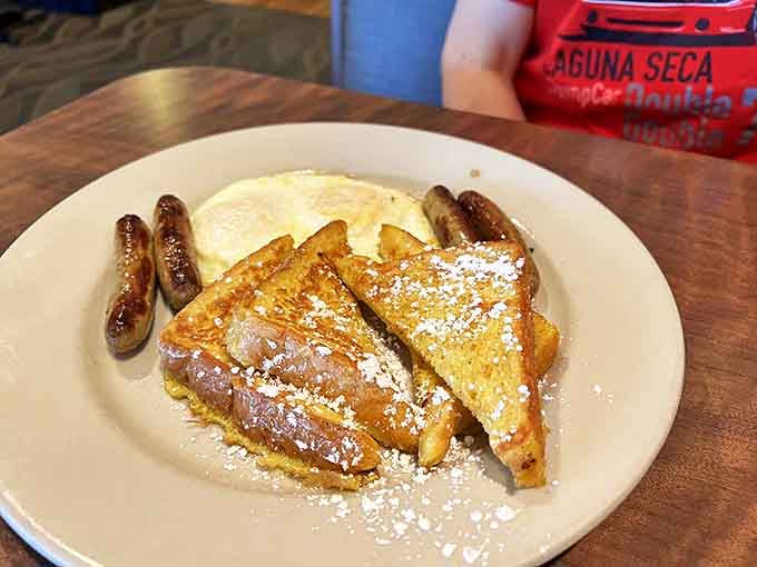 Golden French toast dusted with powdered sugar alongside sausage links &ndash; proof that breakfast foods work their magic at any hour.