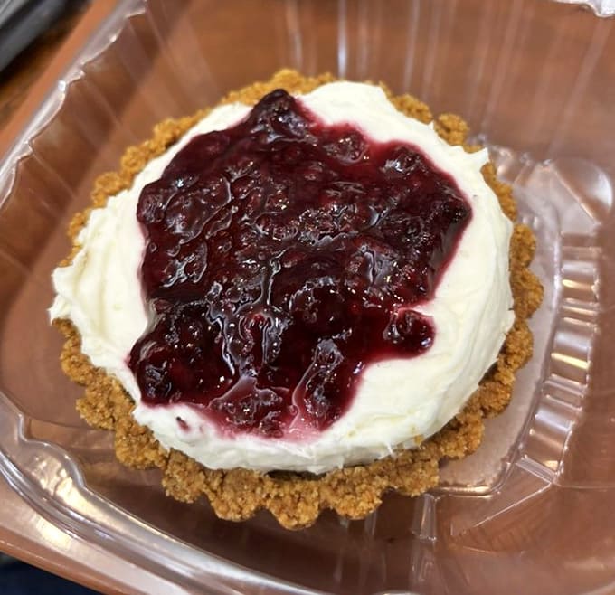 Cheesecake with berry topping sits on a graham cracker crust, ready to make you forget about any diet plans.
