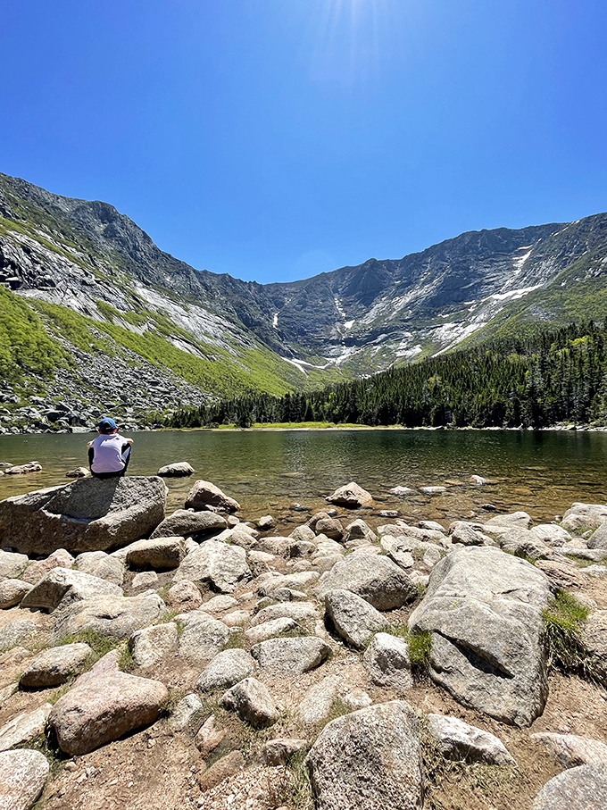 The perfect meditation spot: A lone hiker finds perspective while gazing across crystal waters at Maine's highest peak.