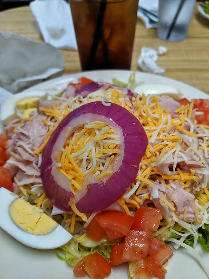 The chef salad arrives like an edible color wheel, with that perfect red onion ring crowning a mountain of fresh ingredients.
