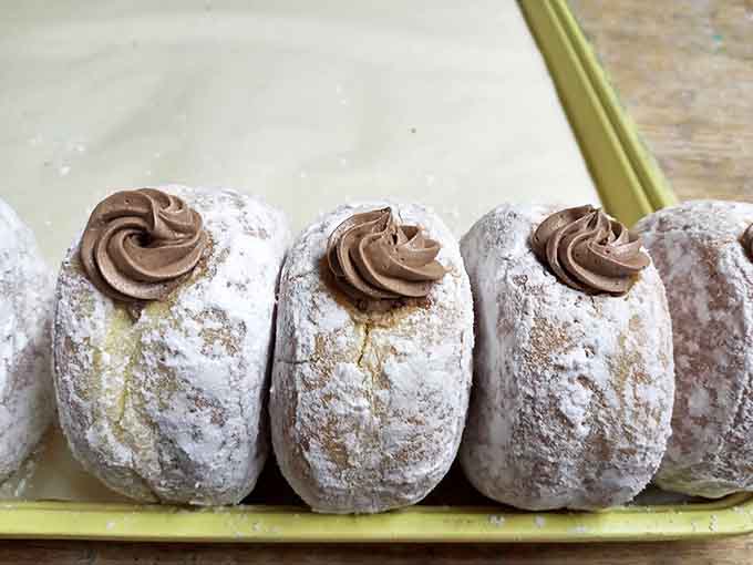 Chocolate cream-filled donuts dusted with powdered sugar and topped with a chocolate rosette, because elegance and indulgence aren't mutually exclusive.