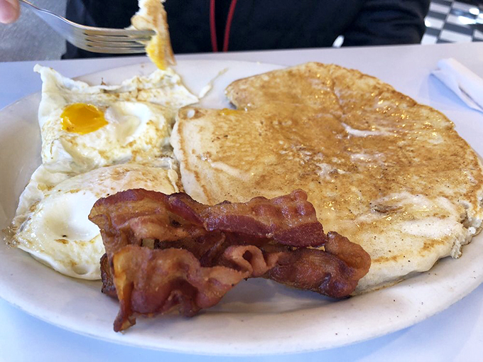The holy trinity of breakfast: eggs, pancakes, and bacon. A plate so perfect, it might just make you believe in morning miracles.