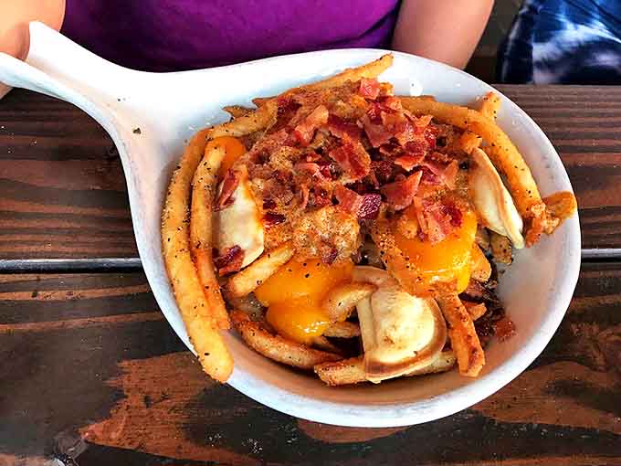 Crispy fries topped with melty cheese, bacon bits, and a sunny-side-up egg create a breakfast-meets-happy-hour masterpiece.