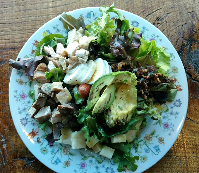 A rainbow of fresh ingredients arranged with care on a vintage plate &ndash; this Cobb salad proves the deli's excellence extends beyond their famous wraps.